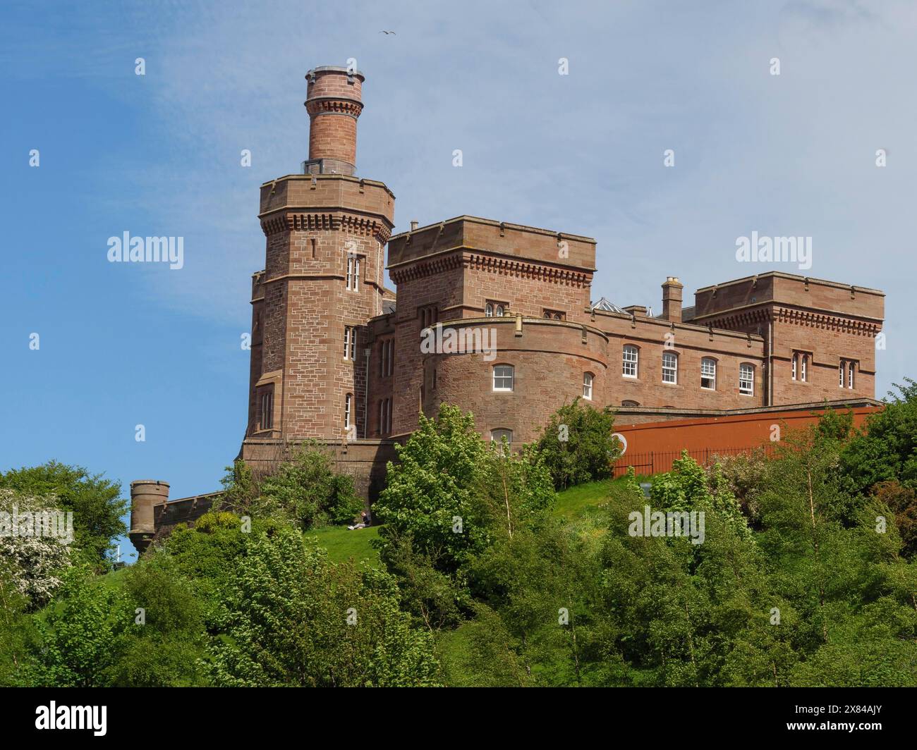 A historic brick castle with several towers, surrounded by trees under ...