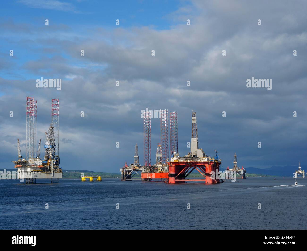 Several oil drilling platforms are standing in the calm sea under a ...