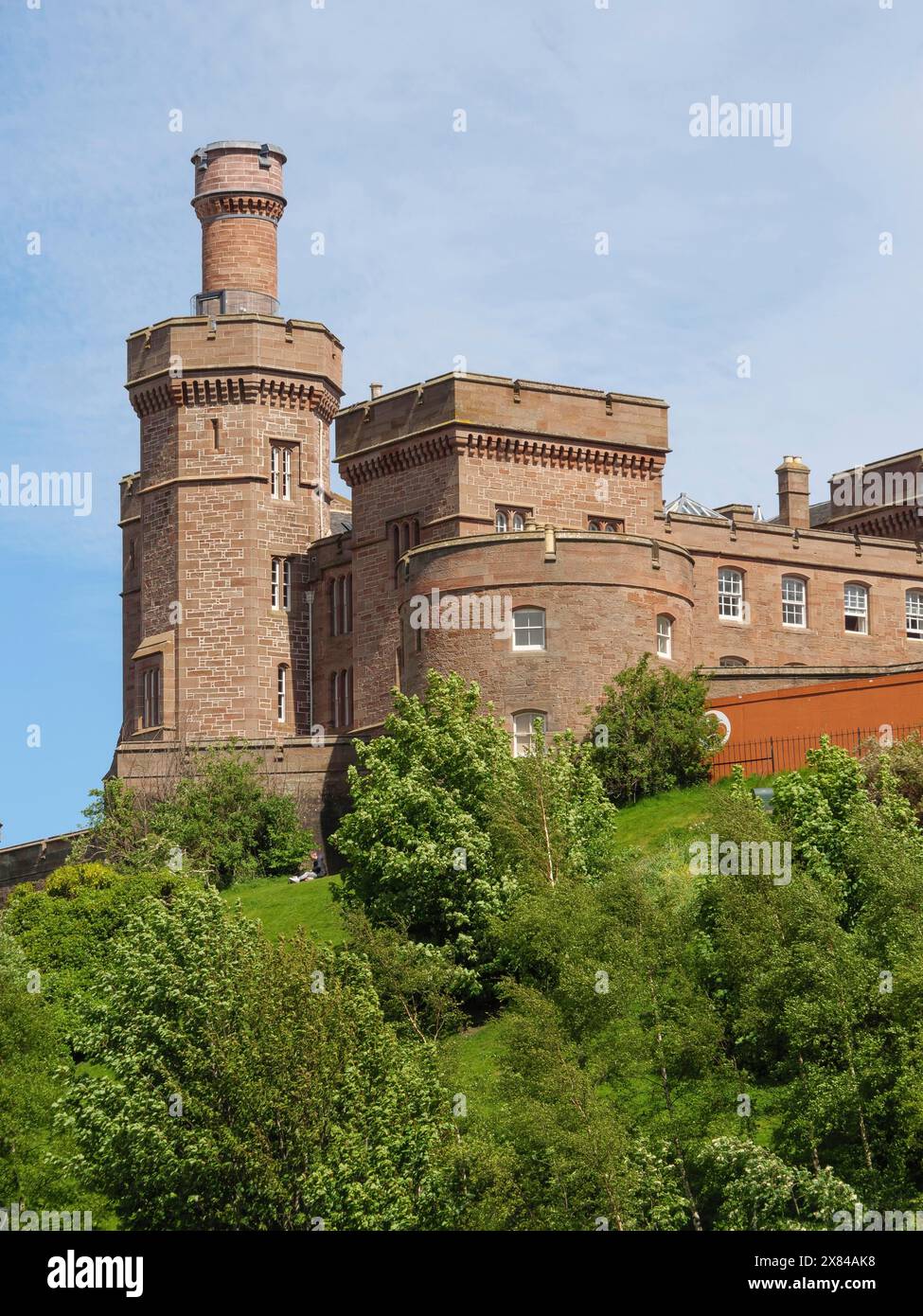 An imposing brick castle with towers, surrounded by green vegetation ...