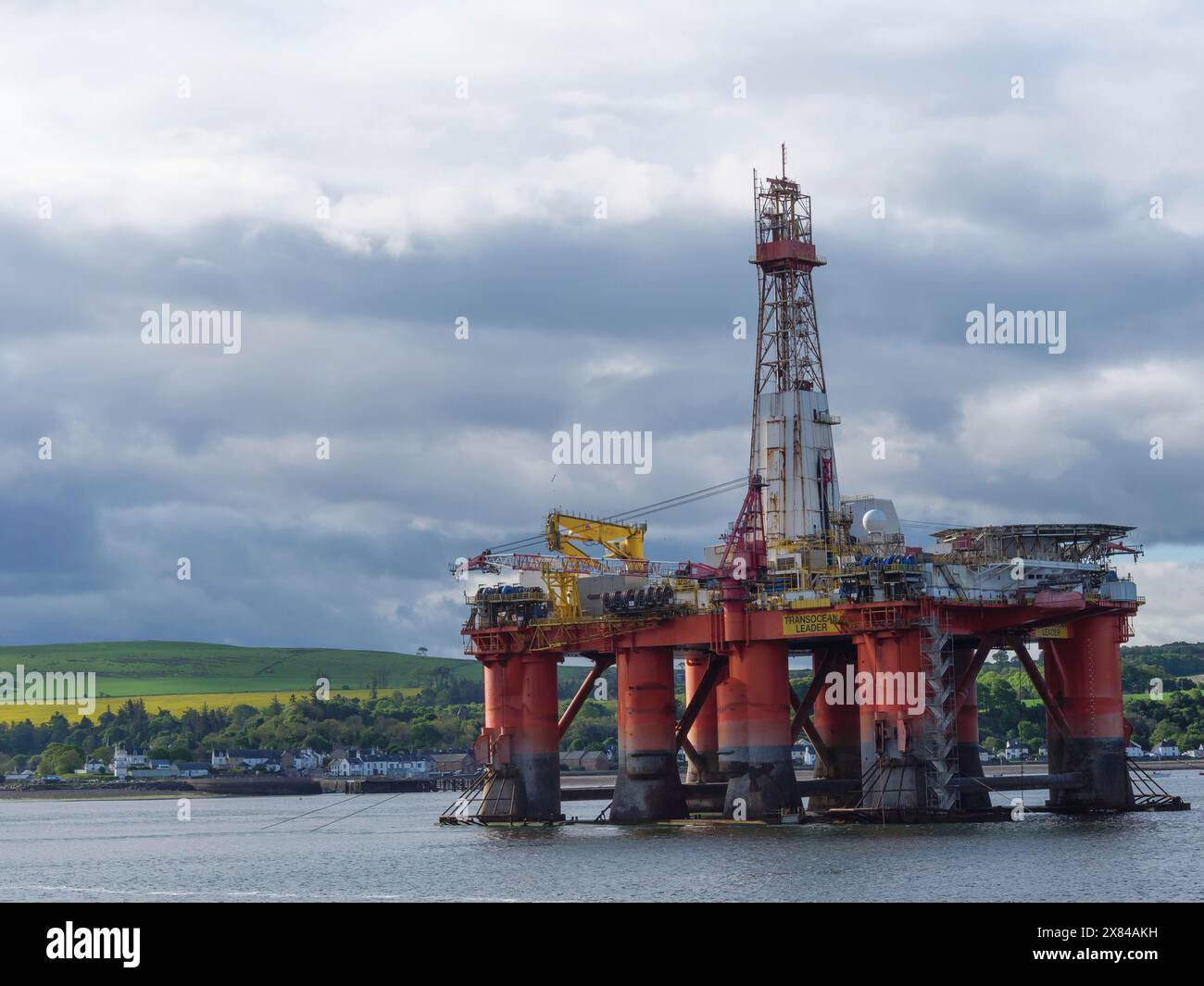 An oil drilling platform stands in the calm sea, behind it a cloudy sky ...