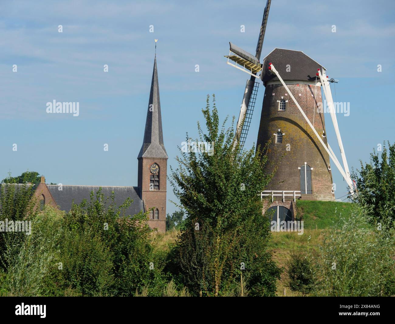 Summer landscape with an old windmill and a high church tower ...