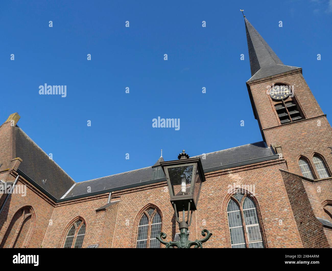 Historic brick church with clock tower under a clear blue sky, village ...