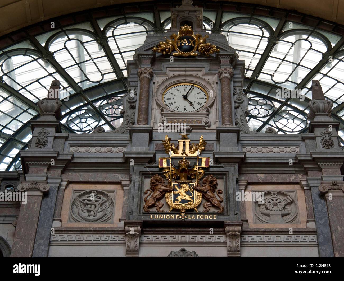 Detailed interior wall with large clock and coat of arms under glass ...
