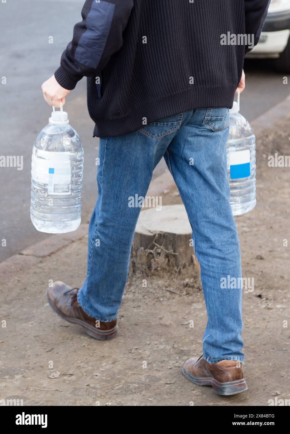 The man carries two bottles of drinking water. Close-up Stock Photo - Alamy