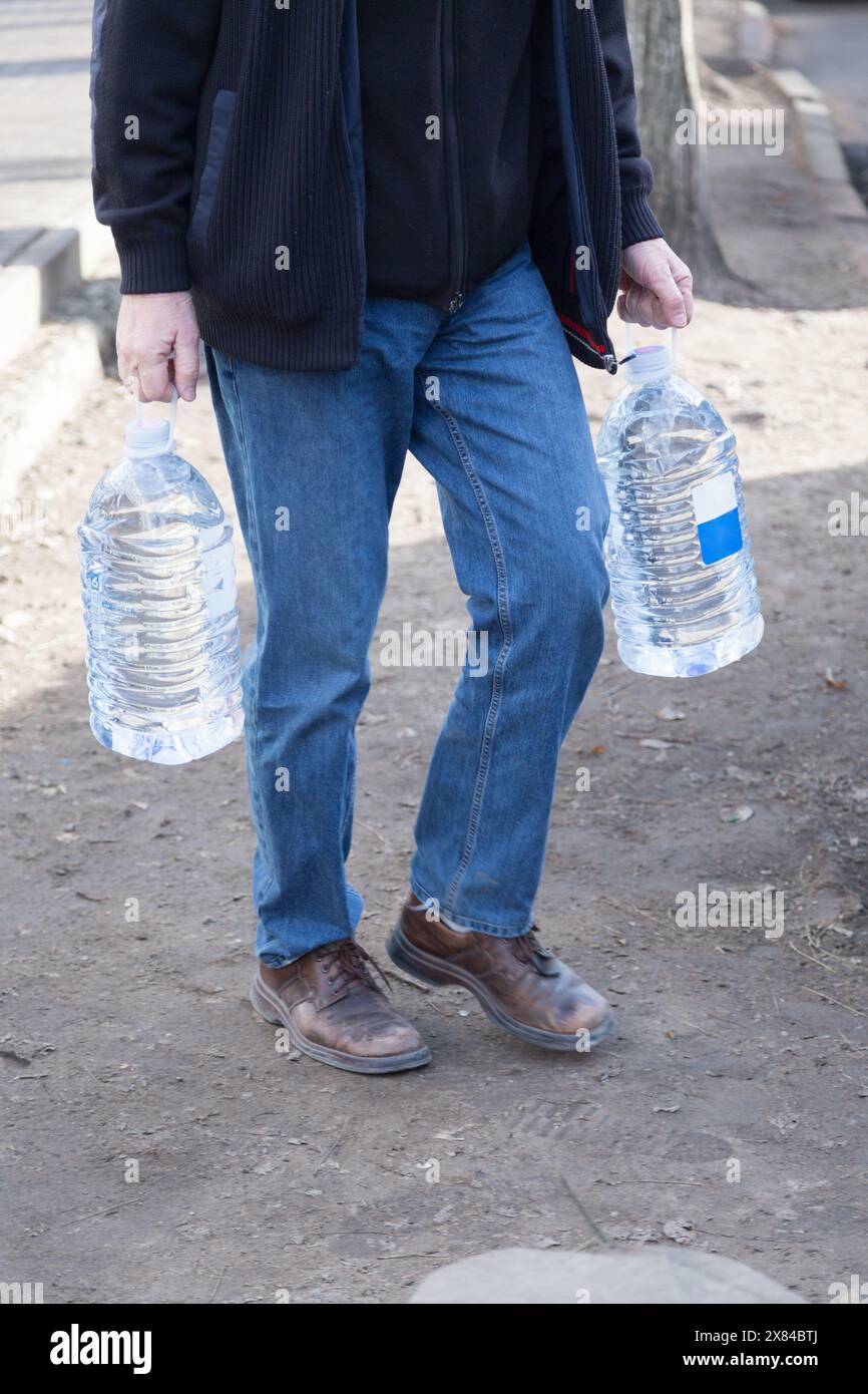 The man carries two bottles of drinking water. Close-up Stock Photo - Alamy