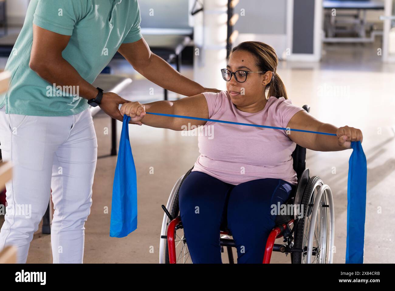 Biracial paraplegic woman in wheelchair using resistance band at ...