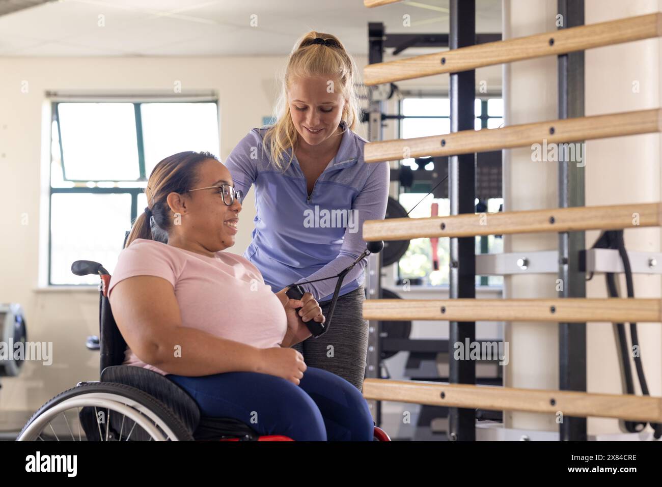 Caucasian female therapist and biracial paraplegic patient in casual ...