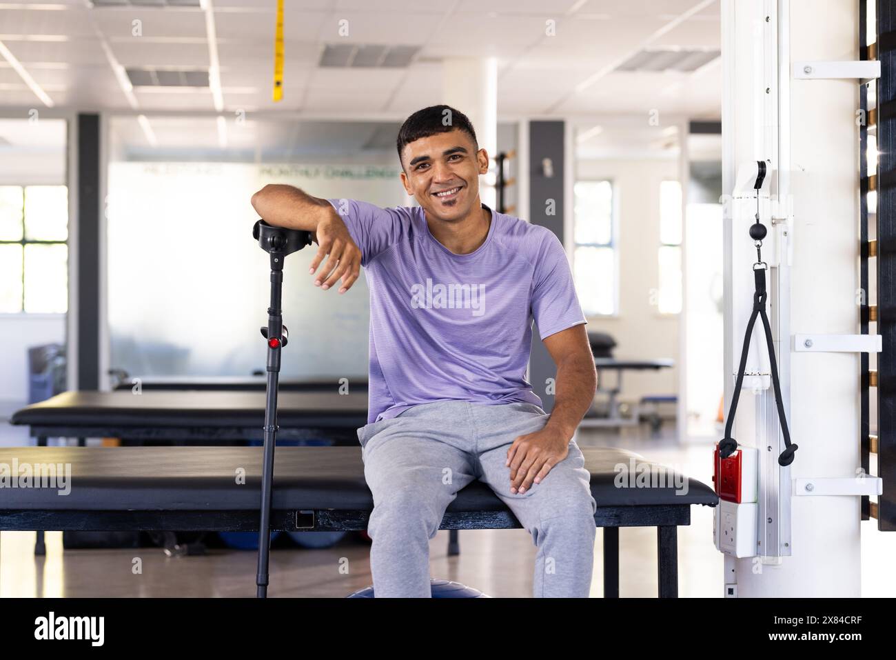 At rehab center, young biracial male patient sits on therapy bench ...