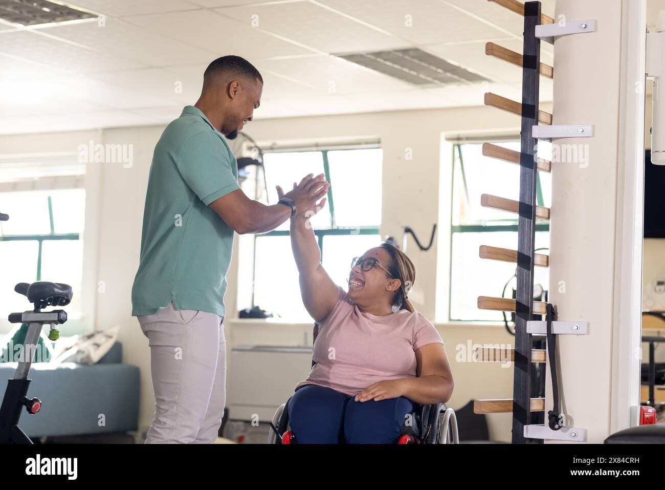 At gym rehab center, biracial male therapist aids biracial female ...