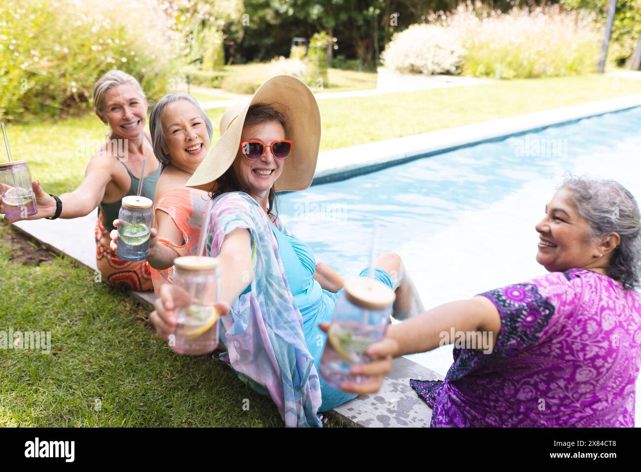 Outdoor gathering of diverse senior female friends enjoying drinks by ...