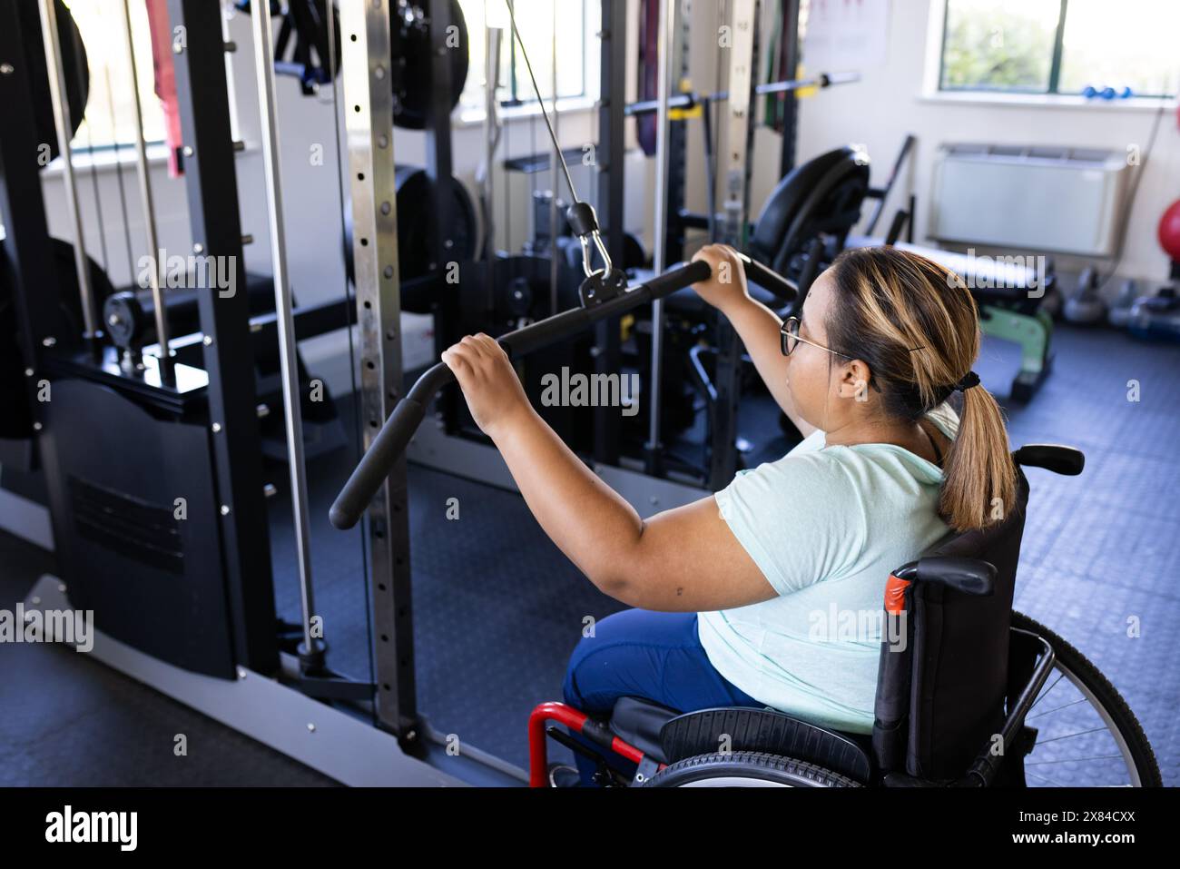 Biracial young paraplegic girl with long brown hair using equipment at ...