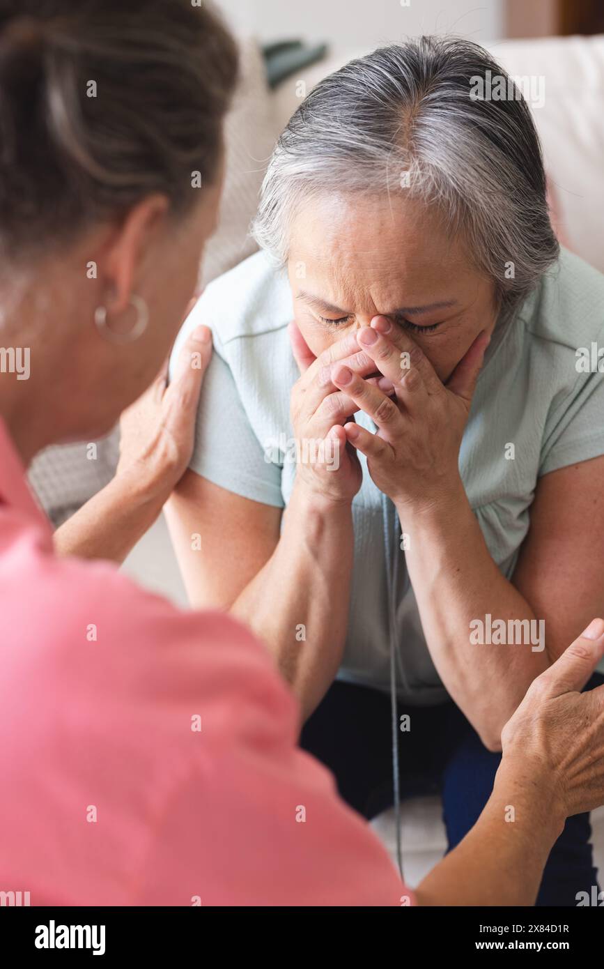 Diverse senior female friends comforting each other at home, looking ...