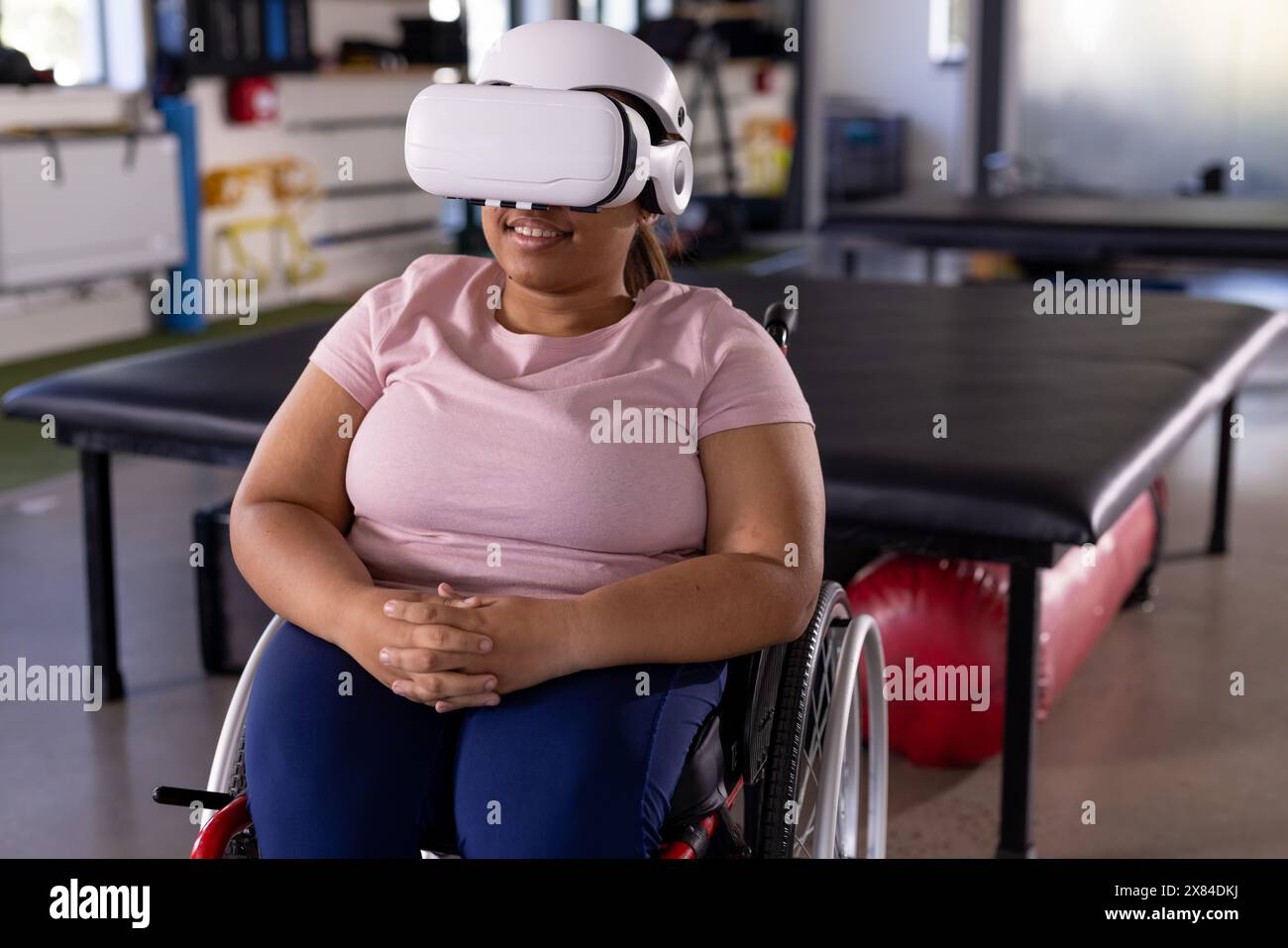 A biracial female paraplegic patient wearing VR headset at gym ...