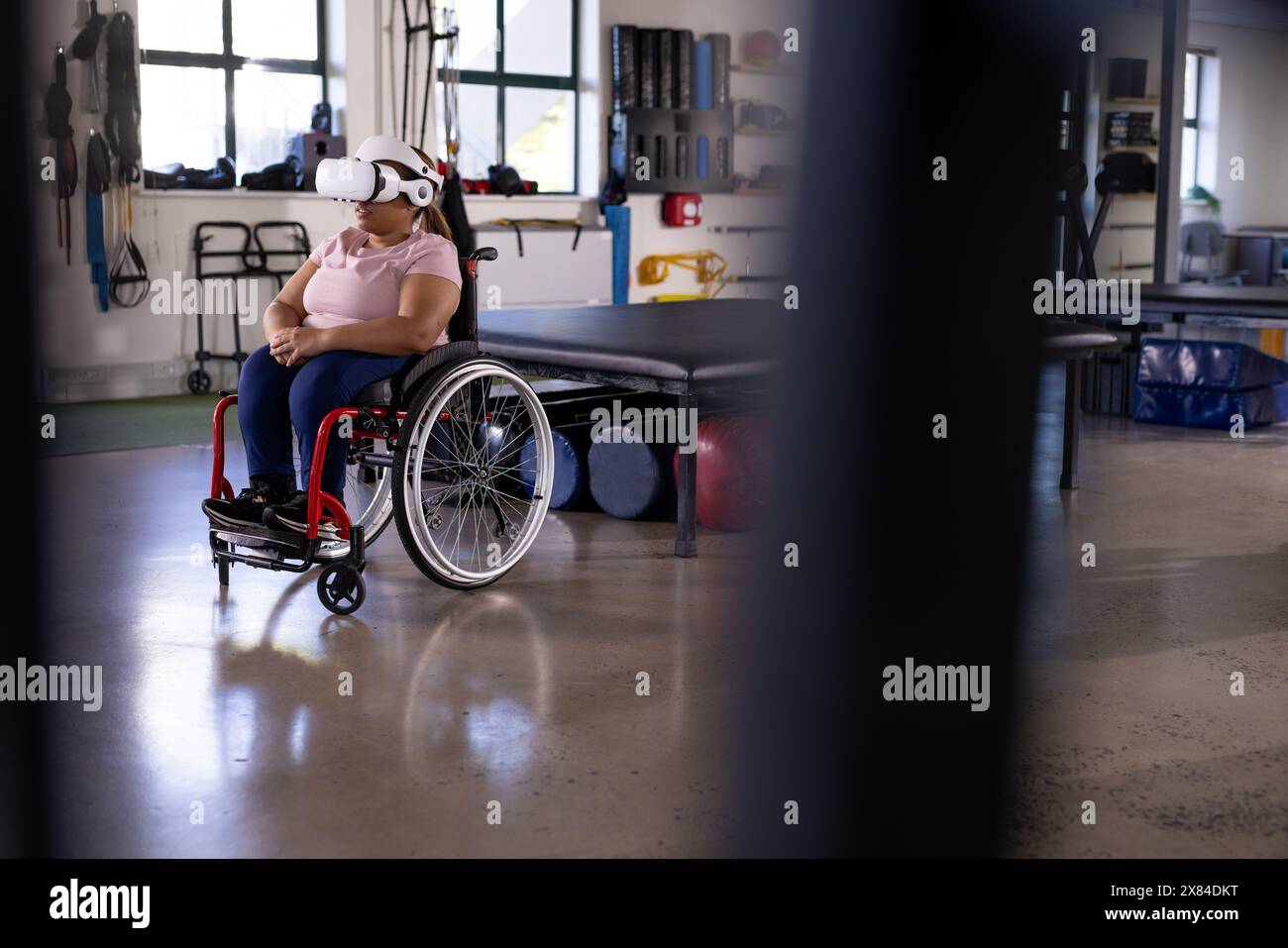 Biracial female paraplegic in wheelchair using VR headset at gym rehab ...