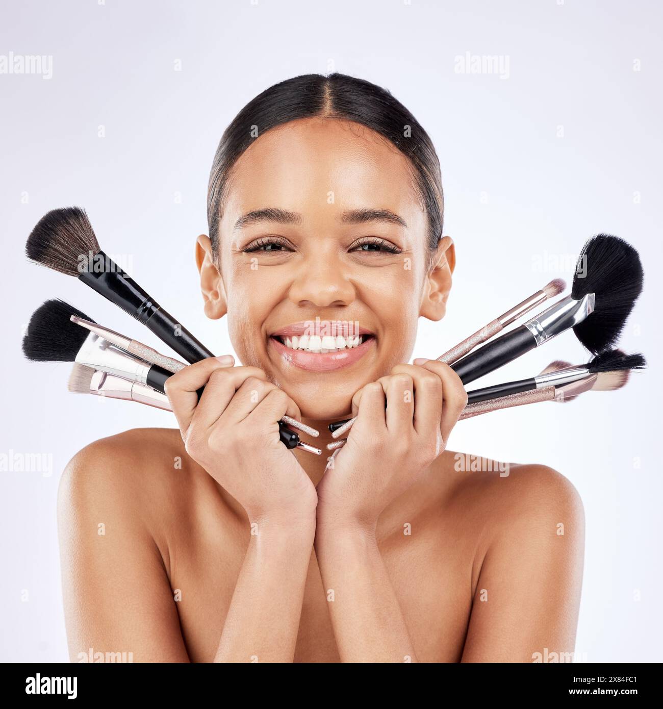 Studio portrait, beauty and happy woman with makeup brushes for ...