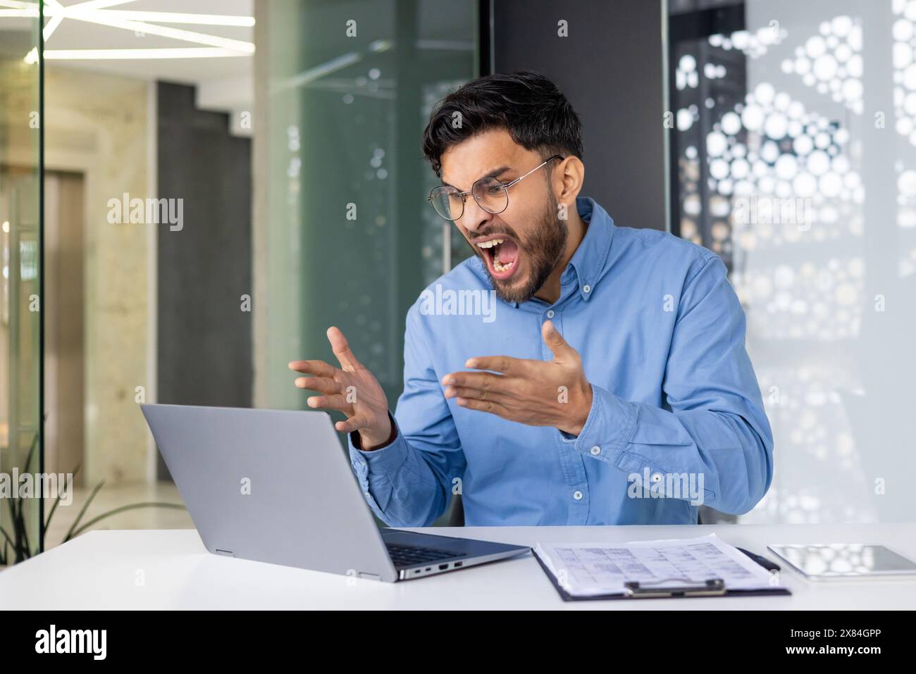 Man expressing frustration and anger at laptop in an office setting ...
