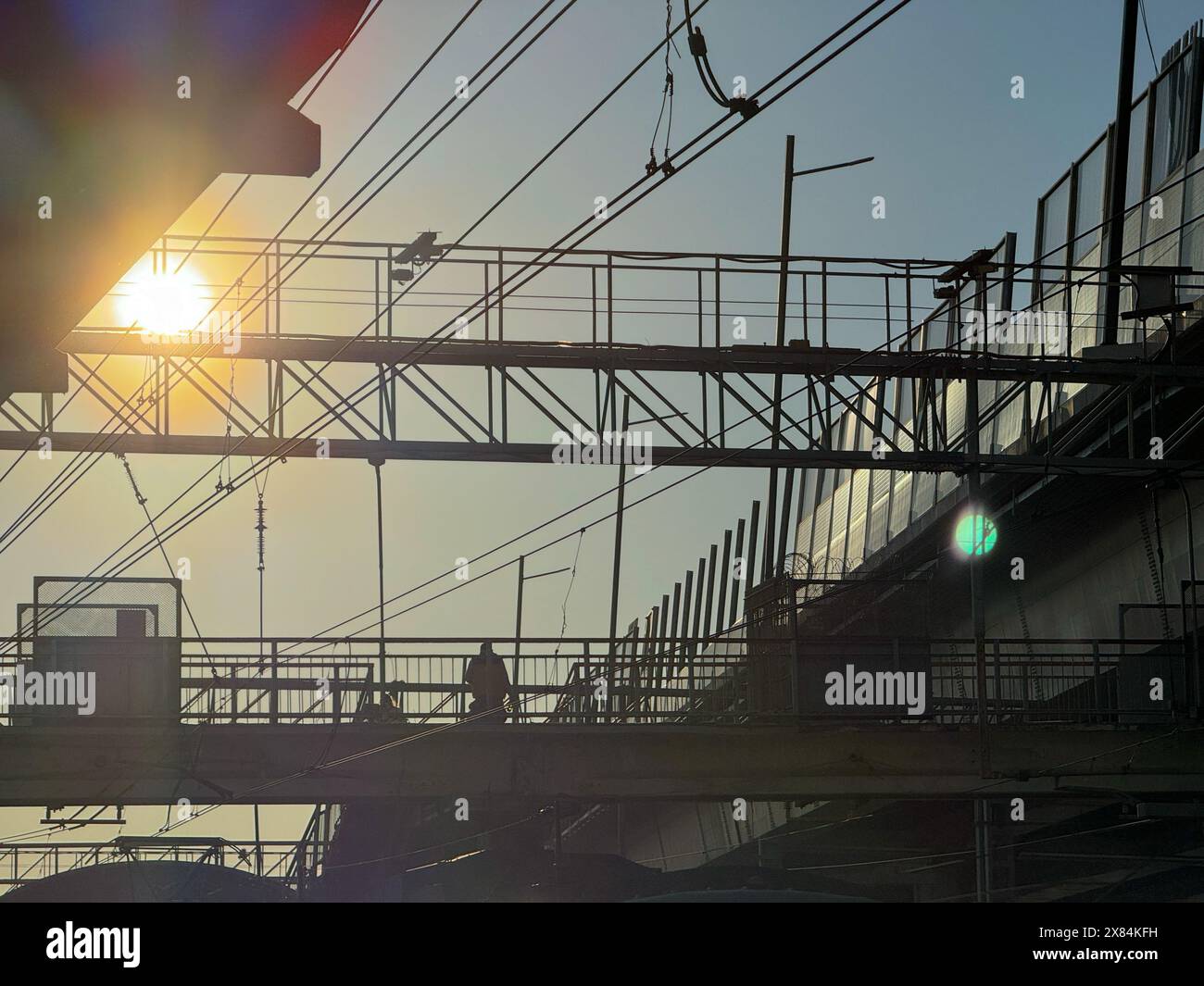 A person walks across an elevated pedestrian bridge silhouetted against ...