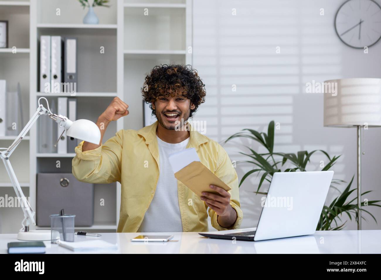 Young man celebrating success while receiving a letter in his home ...