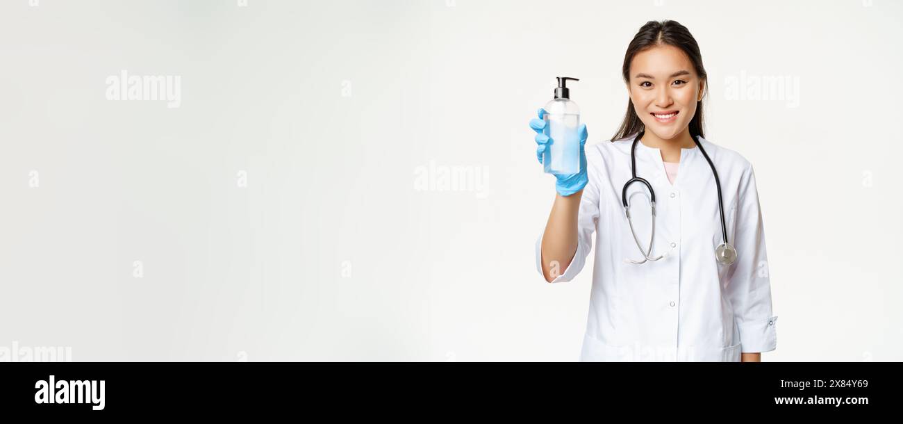 Smiling asian doctor showing hand sanitizer, bottle of antiseptic ...