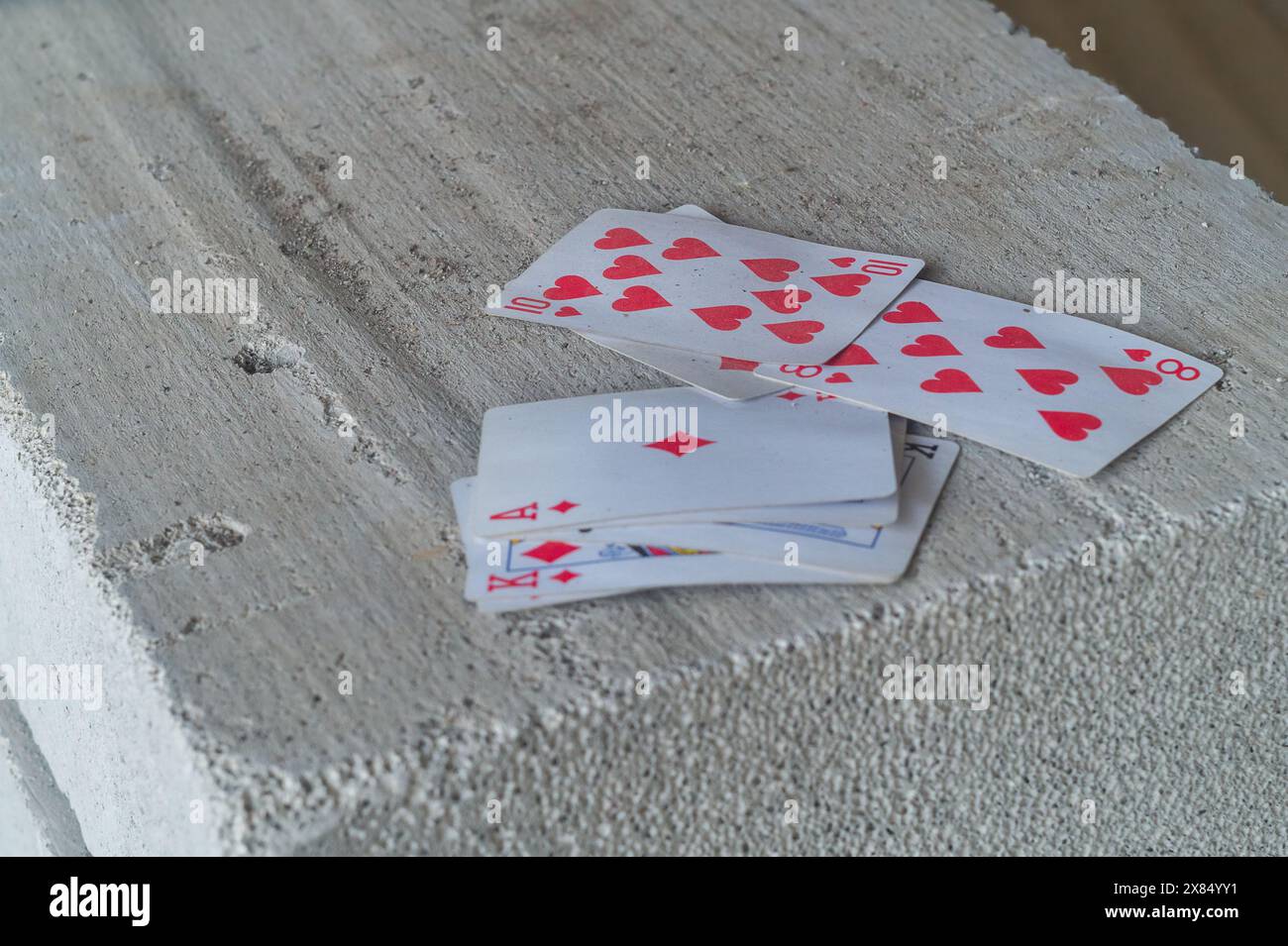 Playing cards of red suits lie on a concrete surface with roughness ...