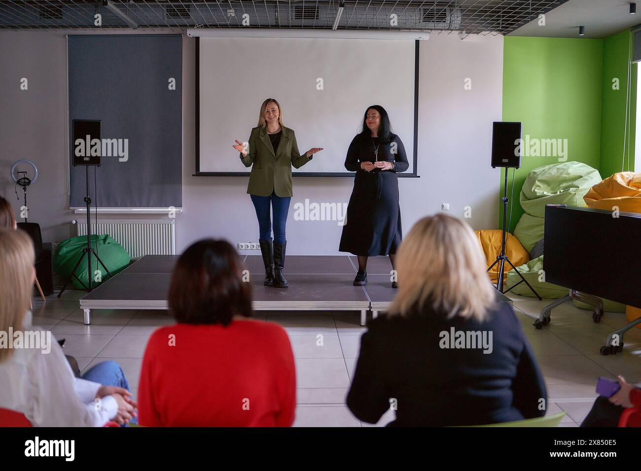 two women give a speech on stage Stock Photo - Alamy