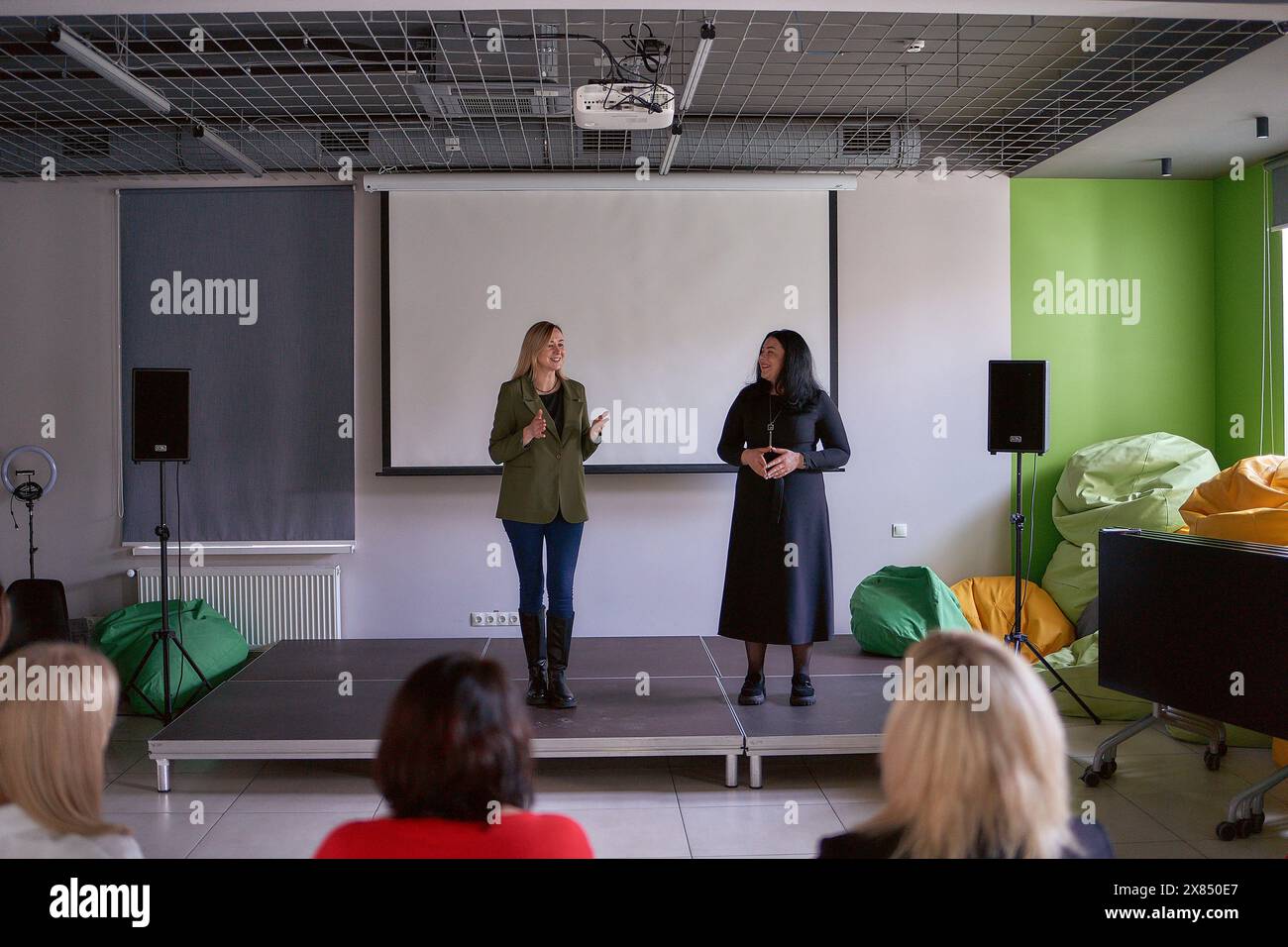 two women give a speech on stage Stock Photo - Alamy
