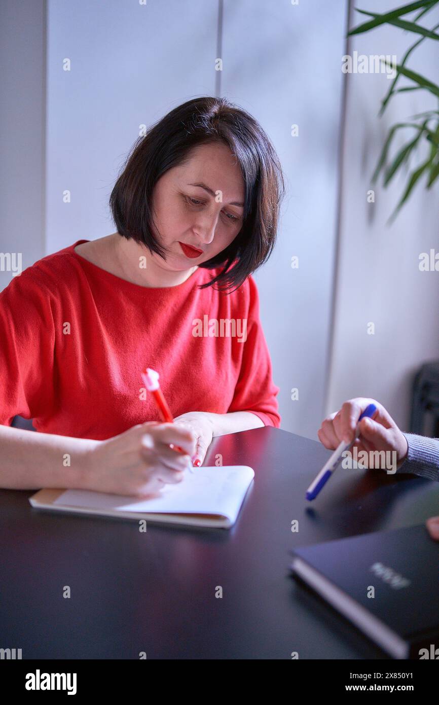 woman is writing down important points at a meeting in the office Stock ...
