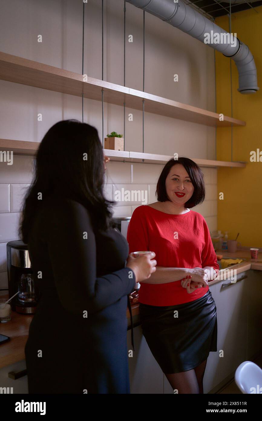 two women talking over coffee in the office kitchen Stock Photo - Alamy