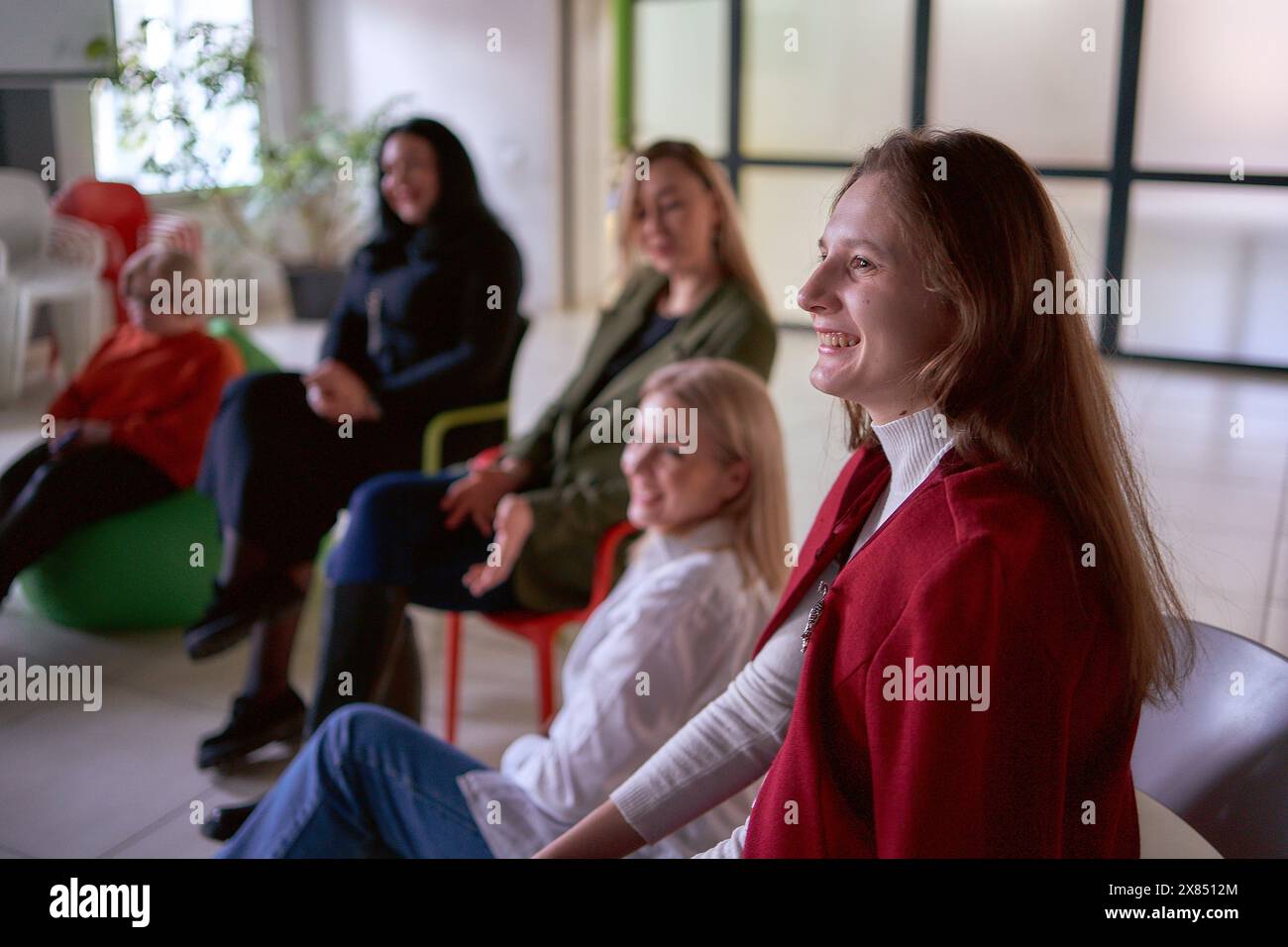 woman makes a speech on stage, colleagues laugh at her jokes sitting on ...