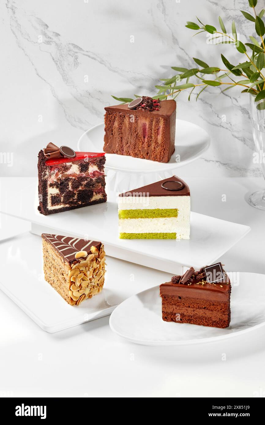 Variety of exquisite cake slices on plates against marble backdrop ...