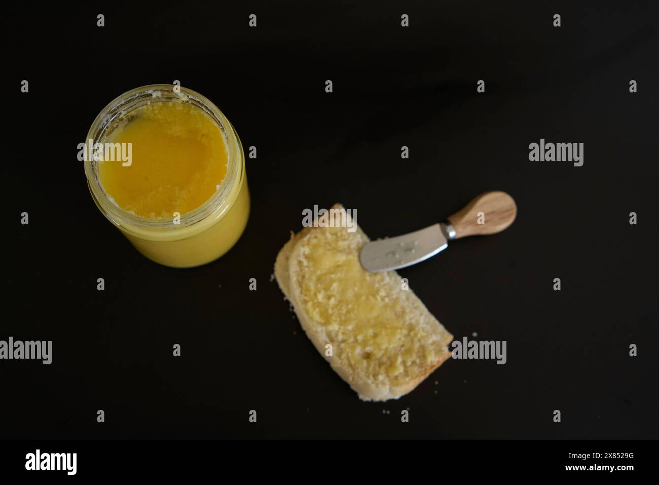 butter ghee in a transparent jar with homemade bread on black ...