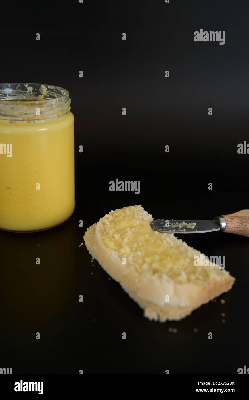 butter ghee in a transparent jar with homemade bread on black ...