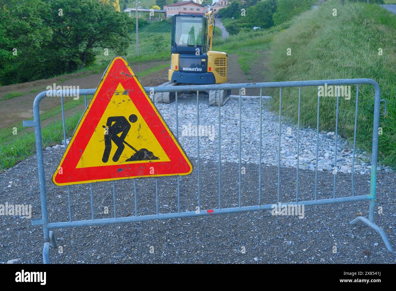 Construction works sign on a road across the metal fence and heavy ...