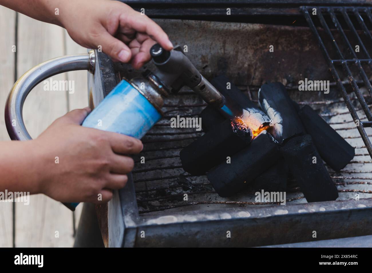 Man using BBQ lighter torch to start fire for charcoal Stock Photo - Alamy
