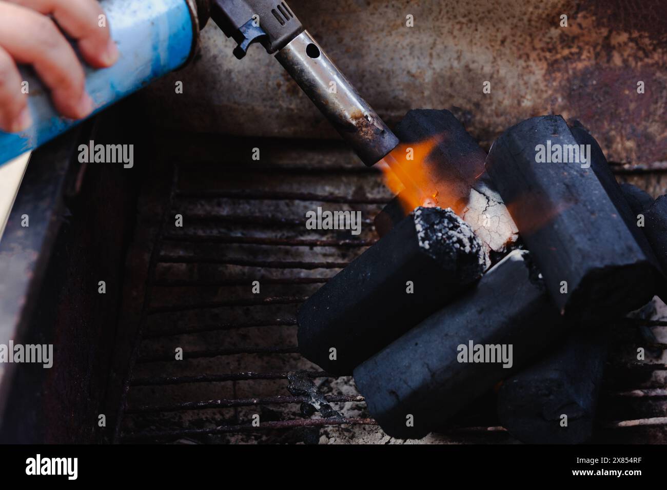 Man using BBQ lighter torch to start fire for charcoal Stock Photo - Alamy
