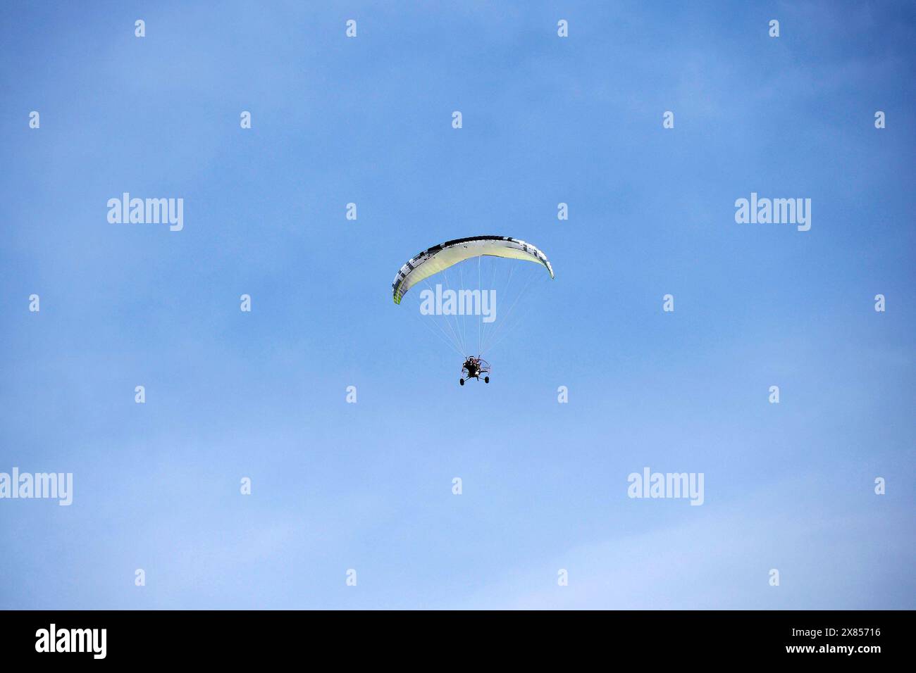 A Powered Motorized paraglider flying against the blue sky outdoor ...