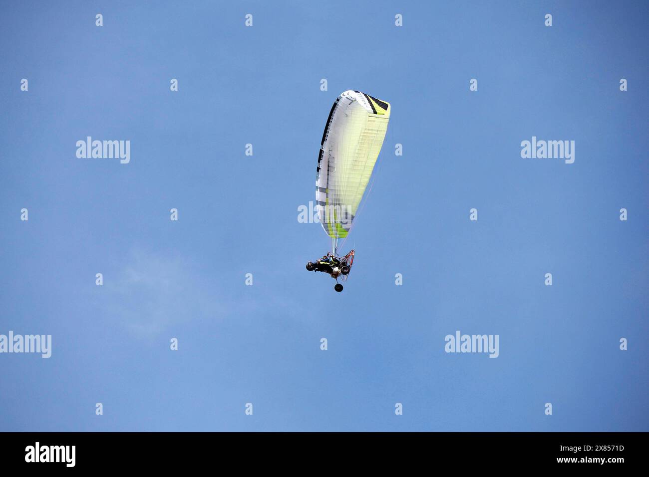 A Powered Motorized paraglider flying against the blue sky outdoor ...