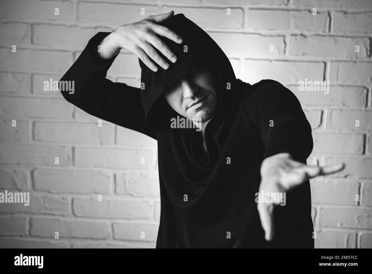 A man wearing a black hoodie is energetically dancing with expressive ...