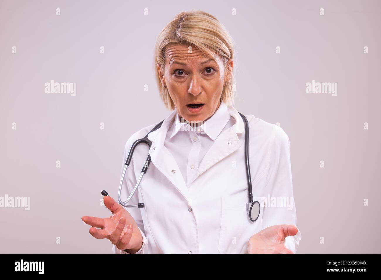 Portrait of shocked mature female doctor on gray background Stock Photo ...