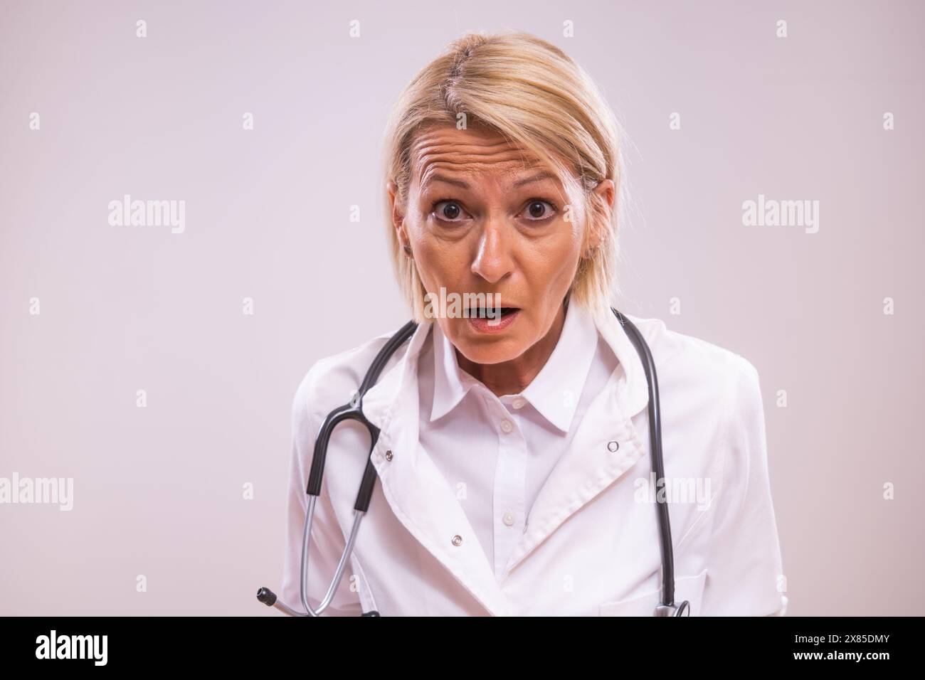 Portrait of shocked mature female doctor on gray background Stock Photo ...