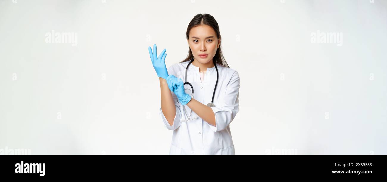 Confident female nurse, physician put on rubber medical gloves for ...