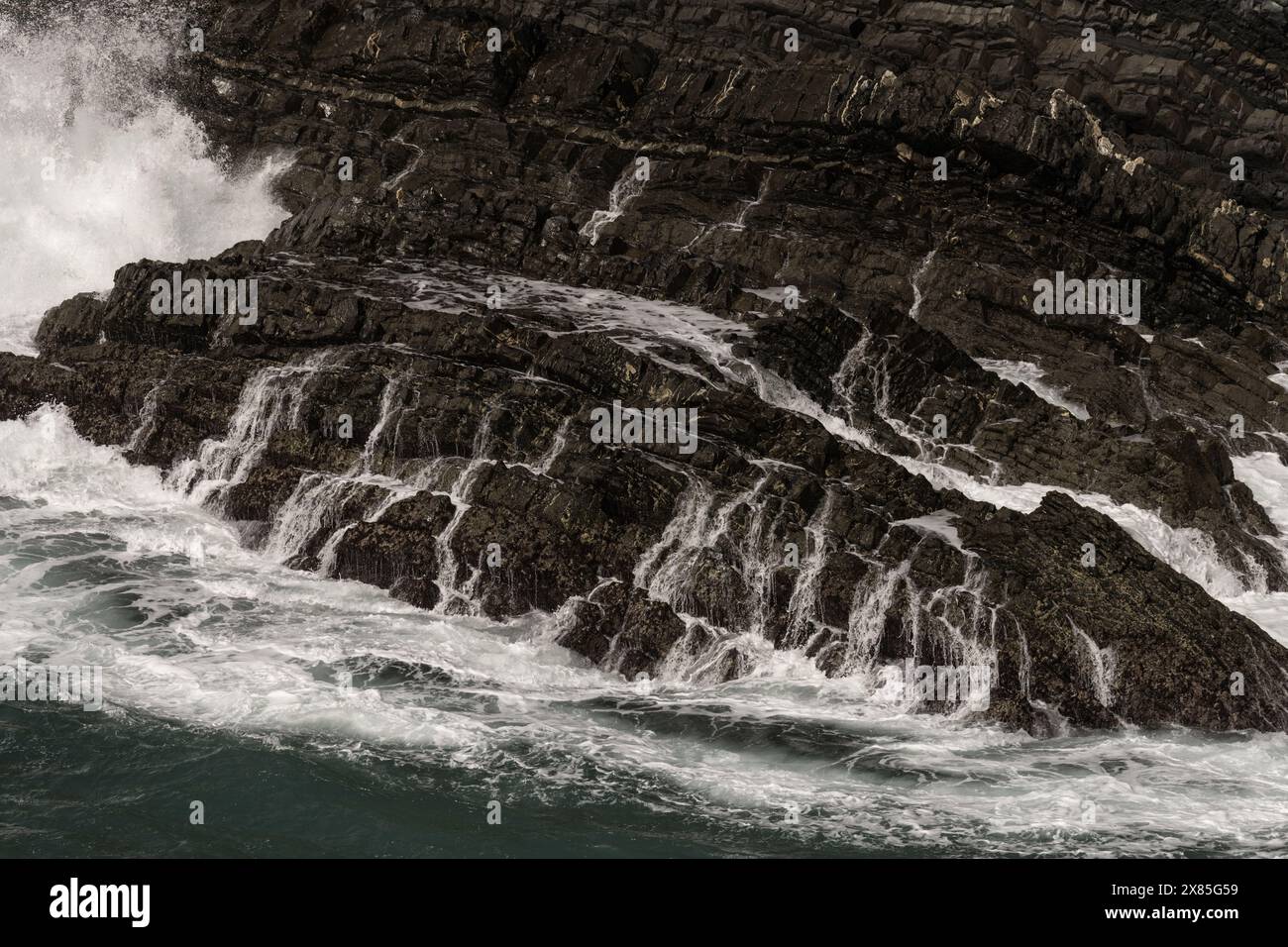 Close-up view of waves forcefully crashing against rugged rocks at Cabo ...