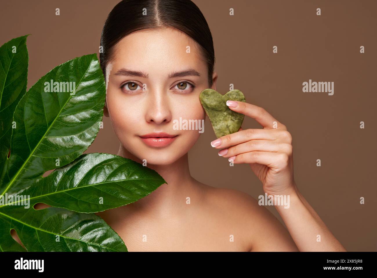 Close up woman face with green exotic leaf. Model doing skin care ...