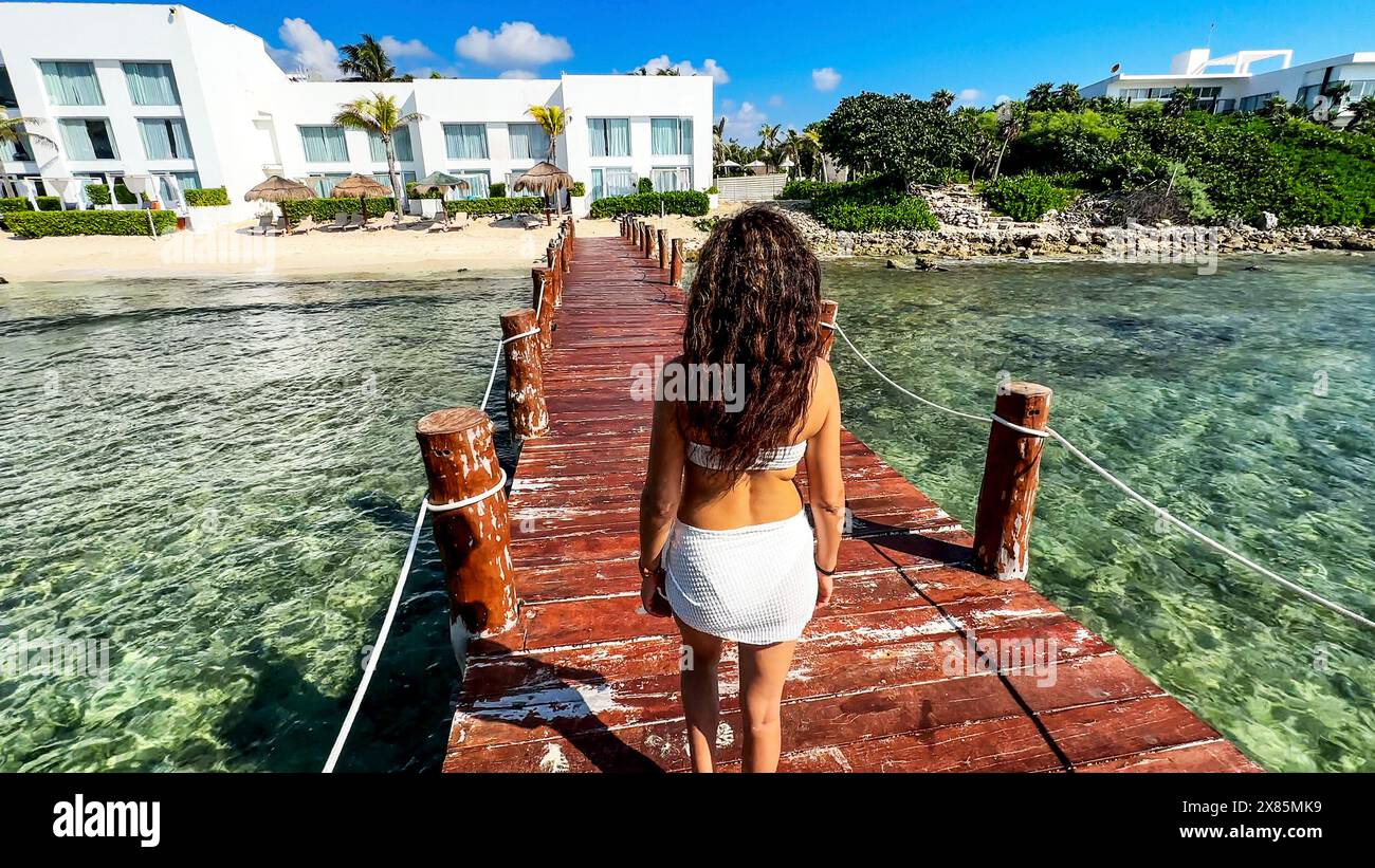 Woman walking along the pier of a paradisiacal beach in the Riviera ...