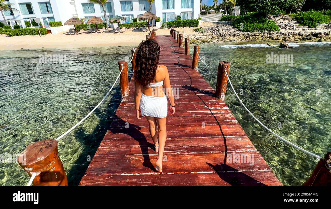 Woman walking along the pier of a paradisiacal beach in the Riviera ...