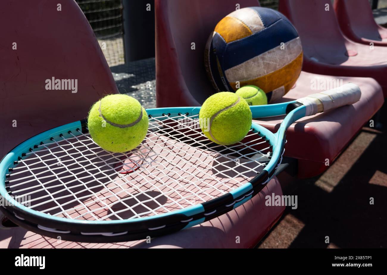 a tennis racket, balls and a volleyball on a bench on the sports ...