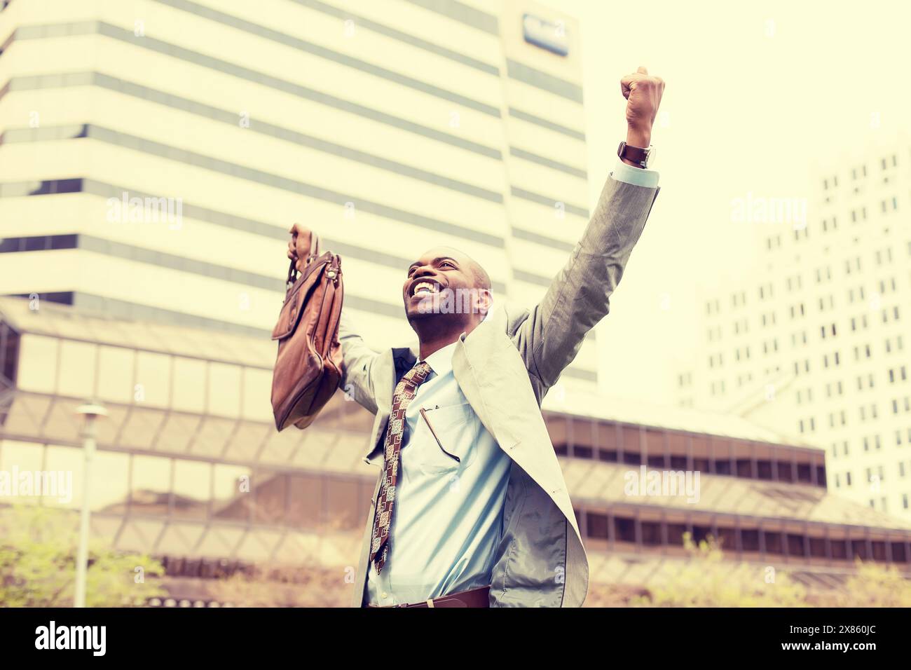 Young business man celebrates freedom success arms raised looking up to ...