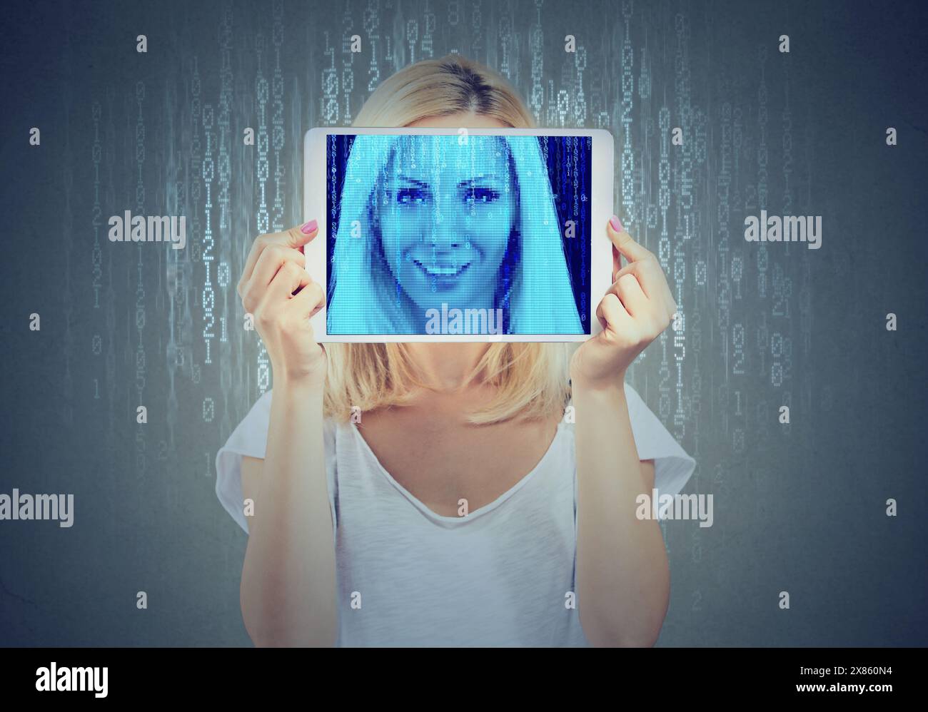 Happy woman holding tablet with her face displayed on a screen with binary code Stock Photo - Alamy