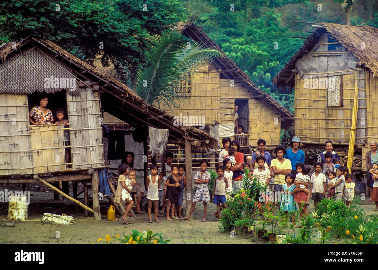 Philippines, Luzon; Residents of a village stand near their bamboo ...