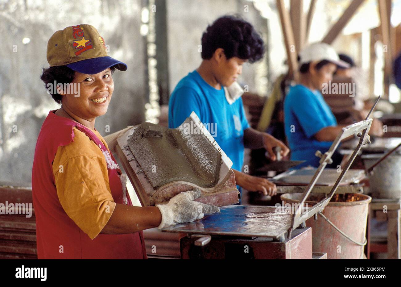 Philippines, Davao Women produce clay roof tiles with a mold at the ...